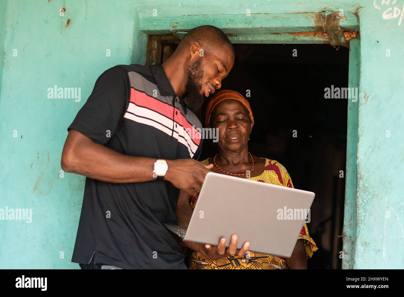 Young African man explaining to an elderly african woman how to use the ...