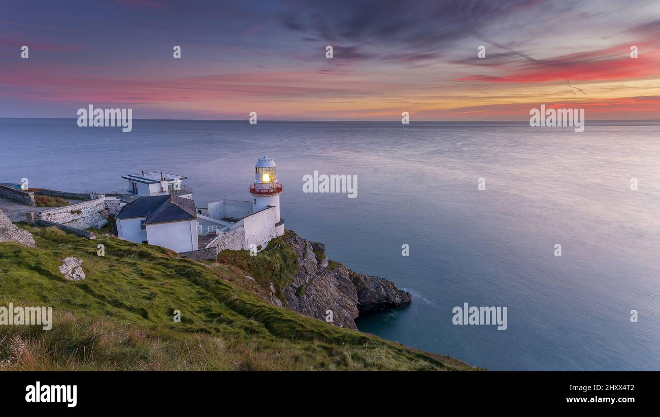 Aerial beautiful view of the Wicklow Head Lighthouse with a sunset sky ...