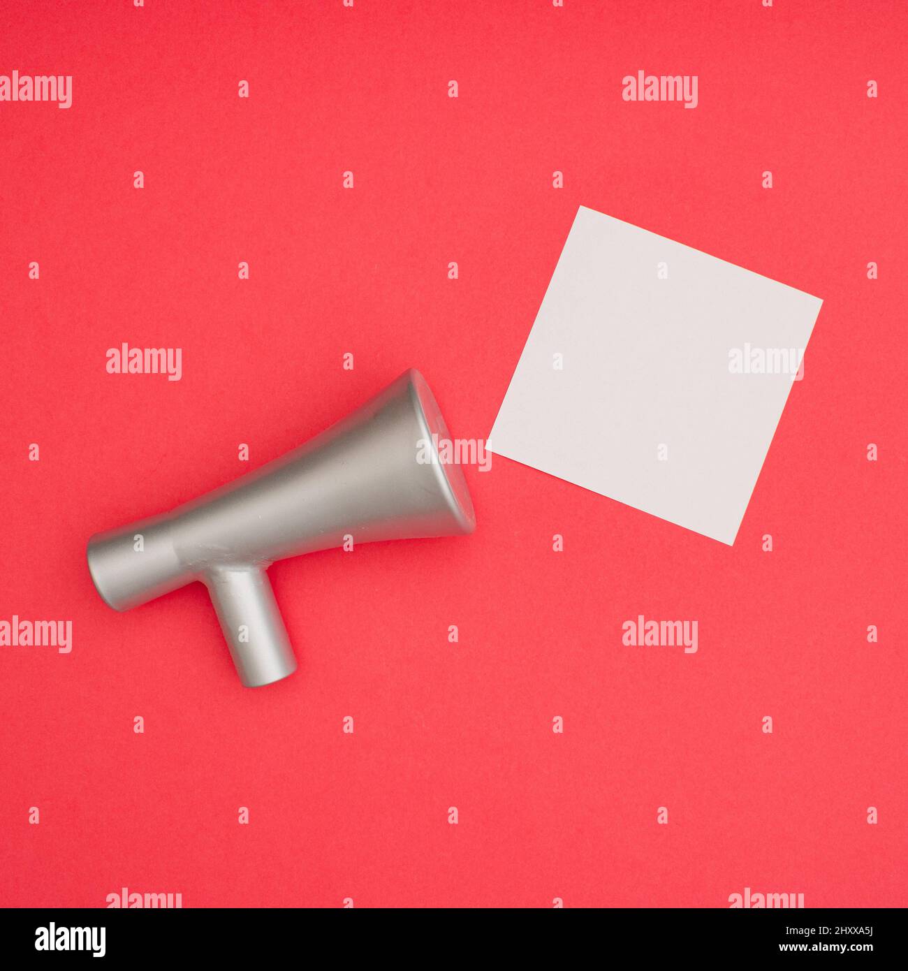 Gray megaphone and sheet of paper with copy space isolated on red ...