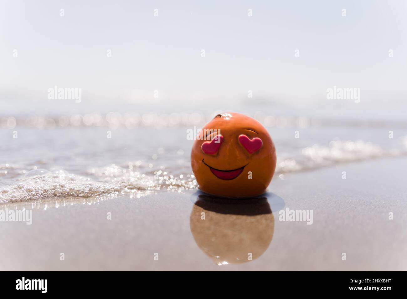 Smiley face with heart eyes dog toy on the beach Stock Photo - Alamy
