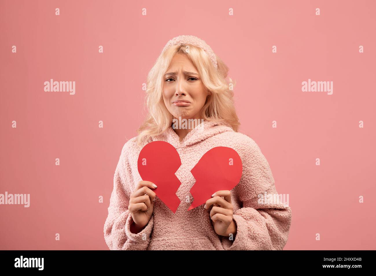 Unhappy lady holding two halves of cut paper heart and crying, feeling ...