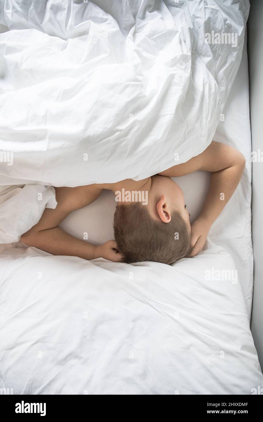 Kid 7 year old lying on bed, Sleepy child waking up the morning in his bed room with morning ...
