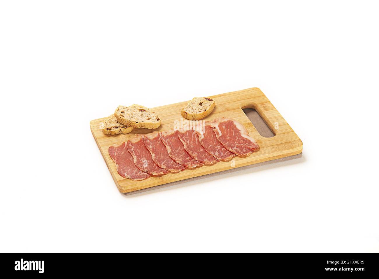 Wooden plank with thin slices of meat and bread on the side isolated on ...