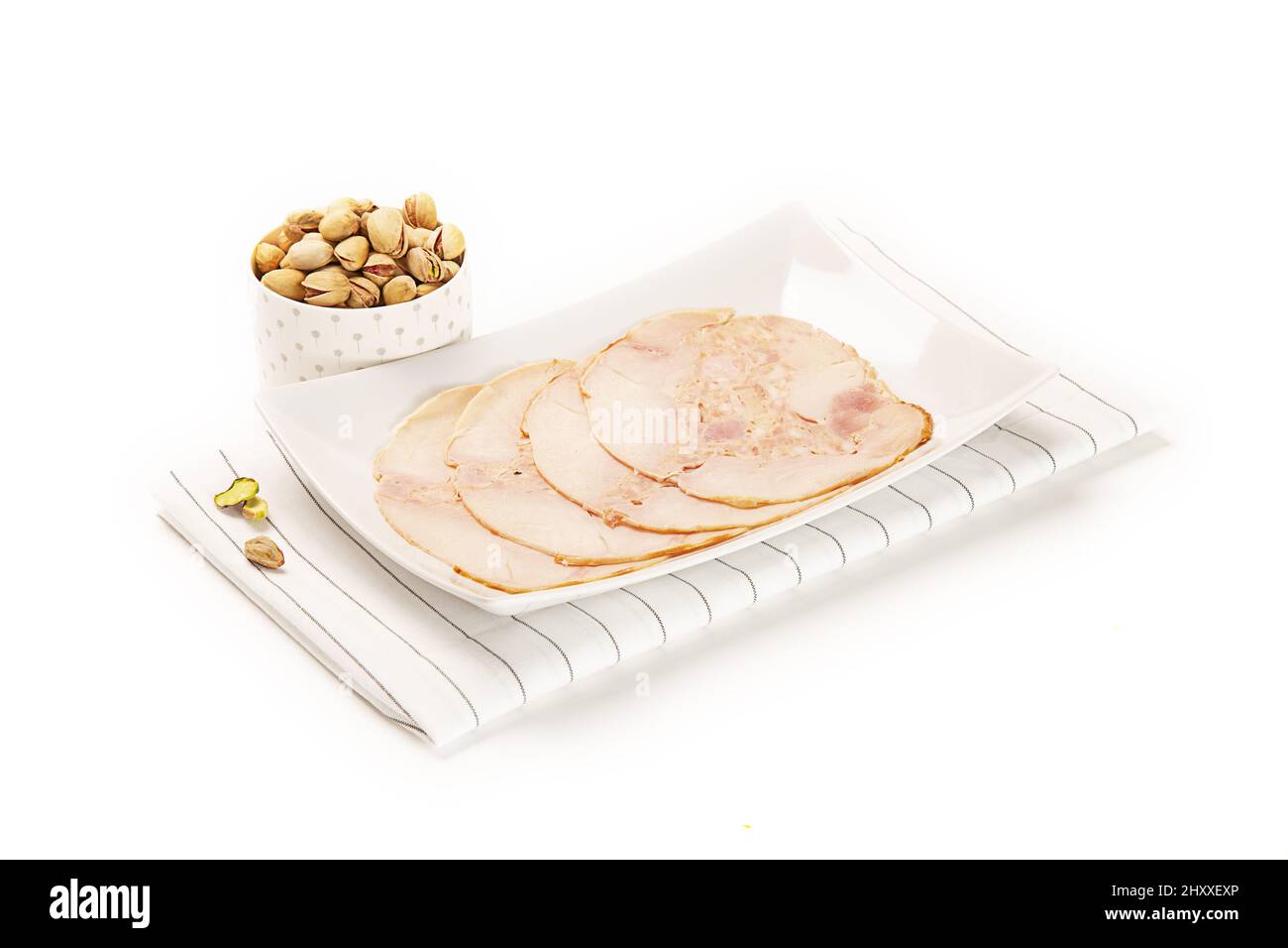 White plate with round slices of meat and nuts on the side isolated on ...