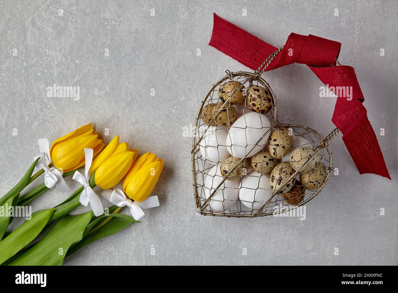 Chicken and quail eggs in a heart shaped woven metal wire box tied with ...