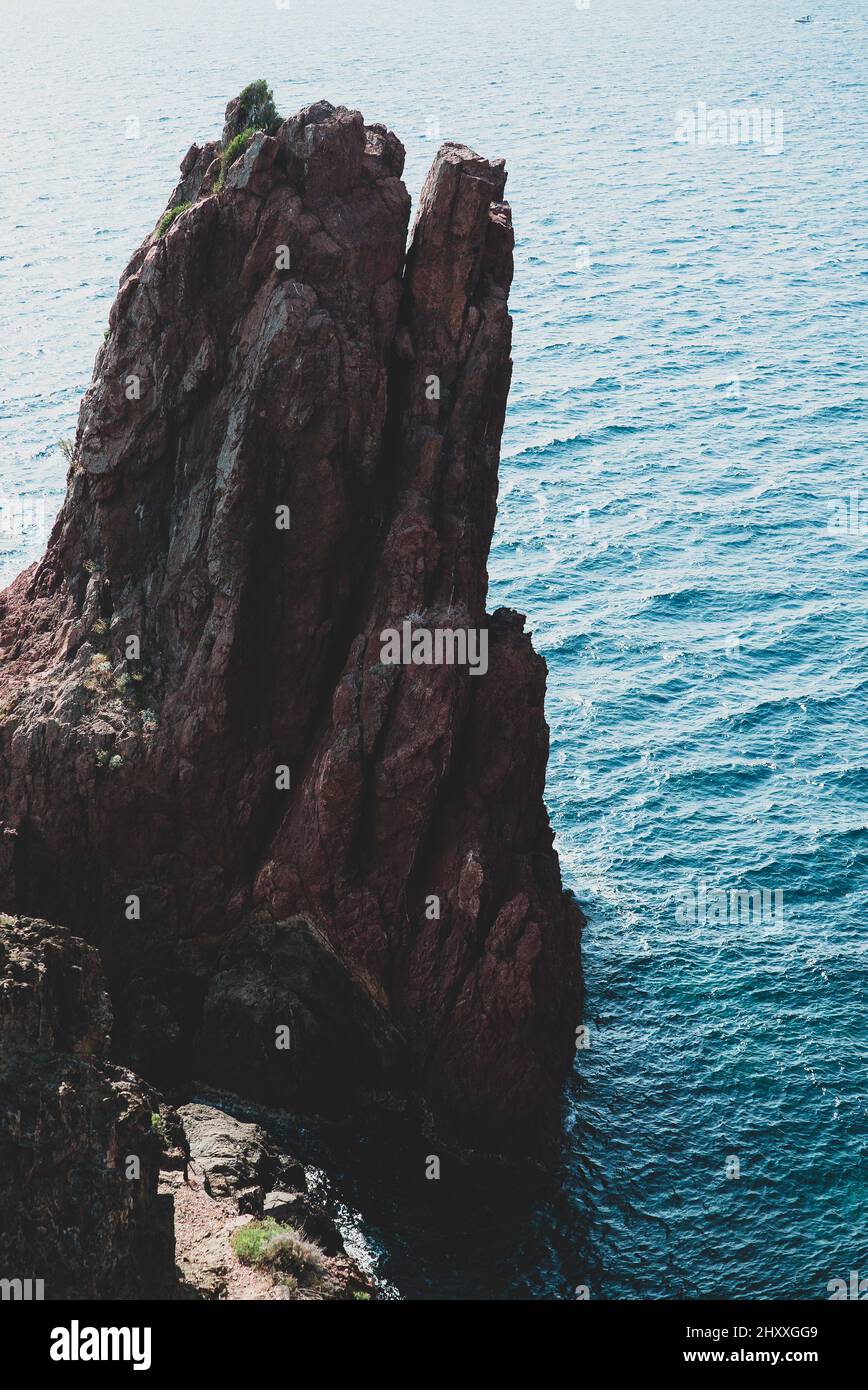 Vertical shot of the cliff by the tranquil water under the sunlight ...
