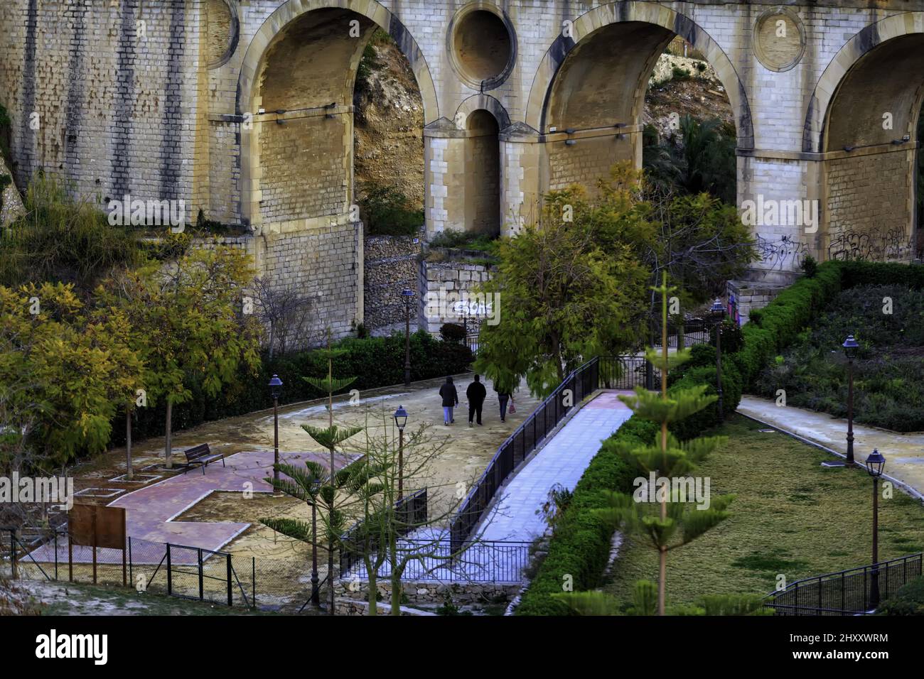 Aerial shot of people under a high stone bridge with arch gates and ...
