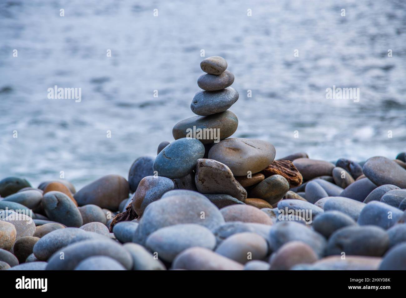 Pebble tower in front of a blurred sea background Stock Photo - Alamy