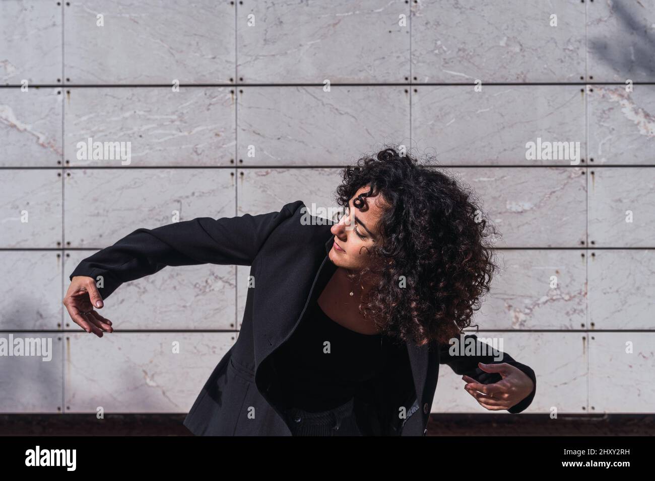 Beautiful Spanish curly woman in a black coat doing hand gestures ...