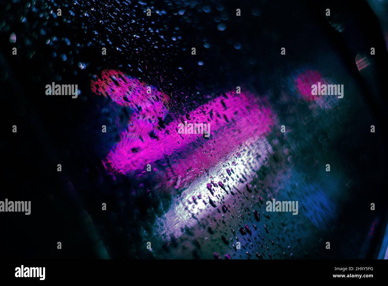 Closeup shot of the rain drops on the car window with the reflection of ...