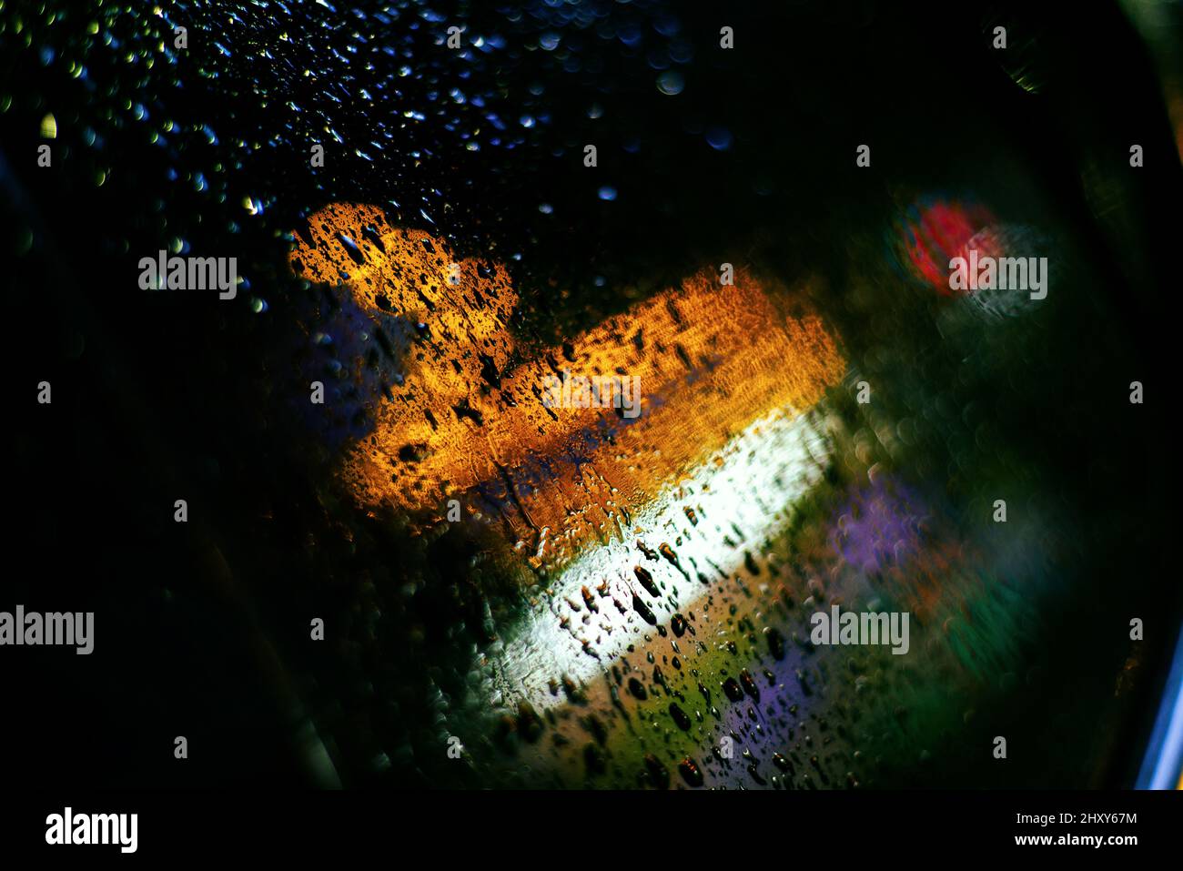 Closeup shot of the rain drops on the car window with the reflection of ...