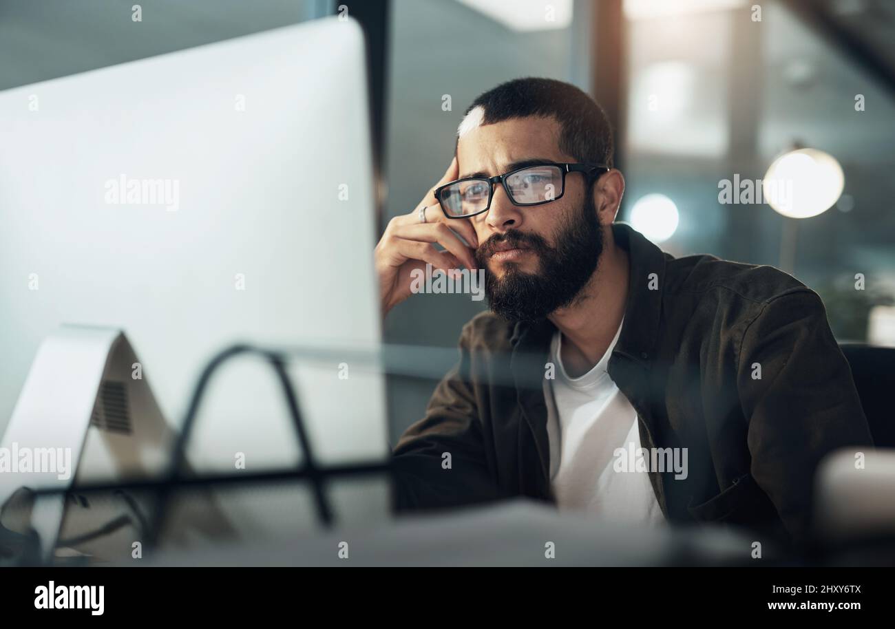The later it gets the deeper he goes. Shot of a young businessman using ...