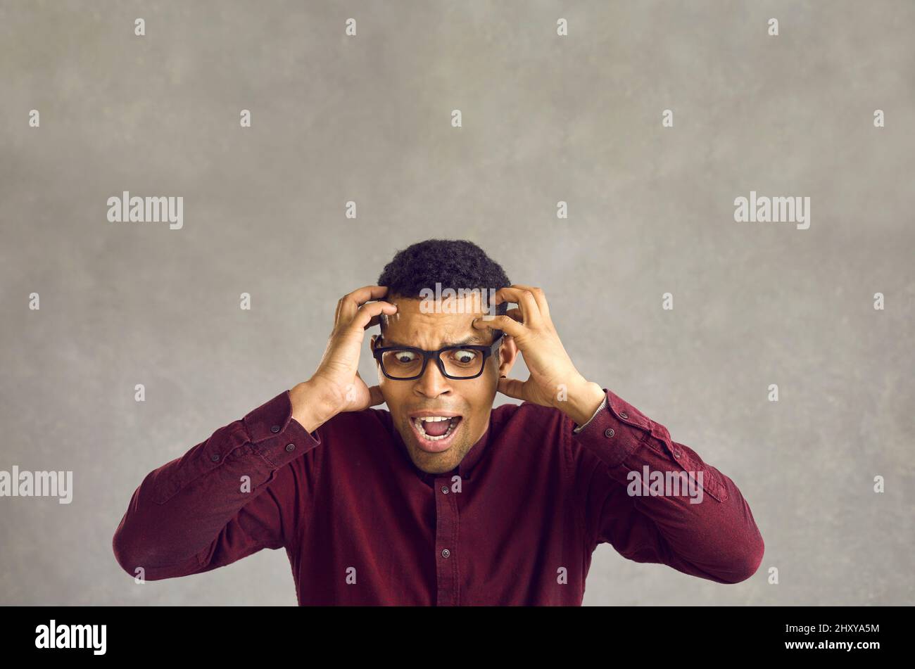 Portrait of scared desperate young black man holding his head and ...