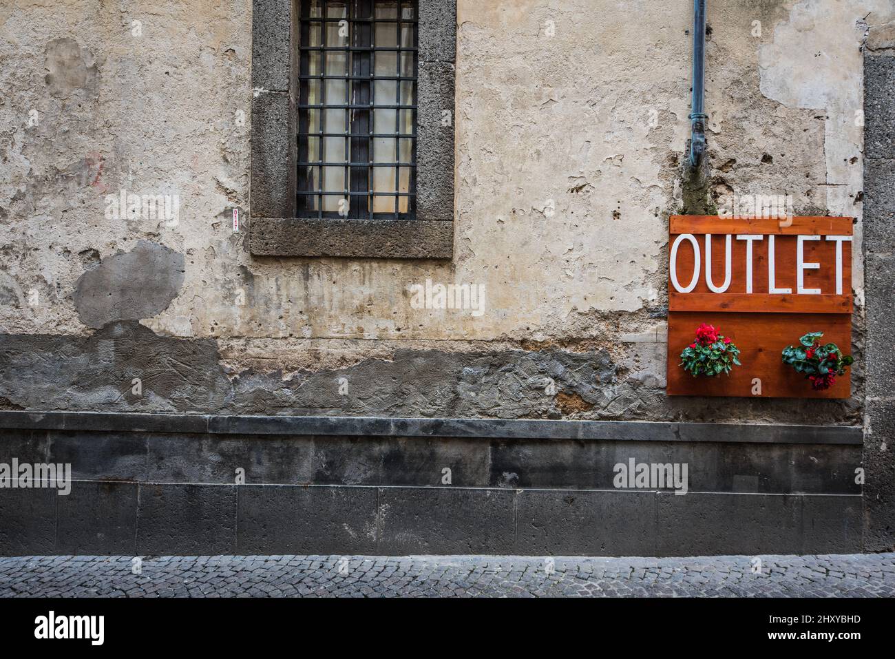 An ancient wall with an old window and a wooden sign next to it with ...
