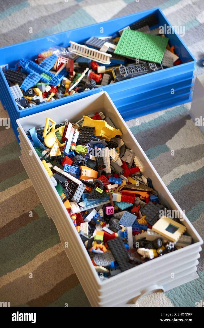 Vertical shot of two full boxes of Lego brand bricks on a carpet floor ...
