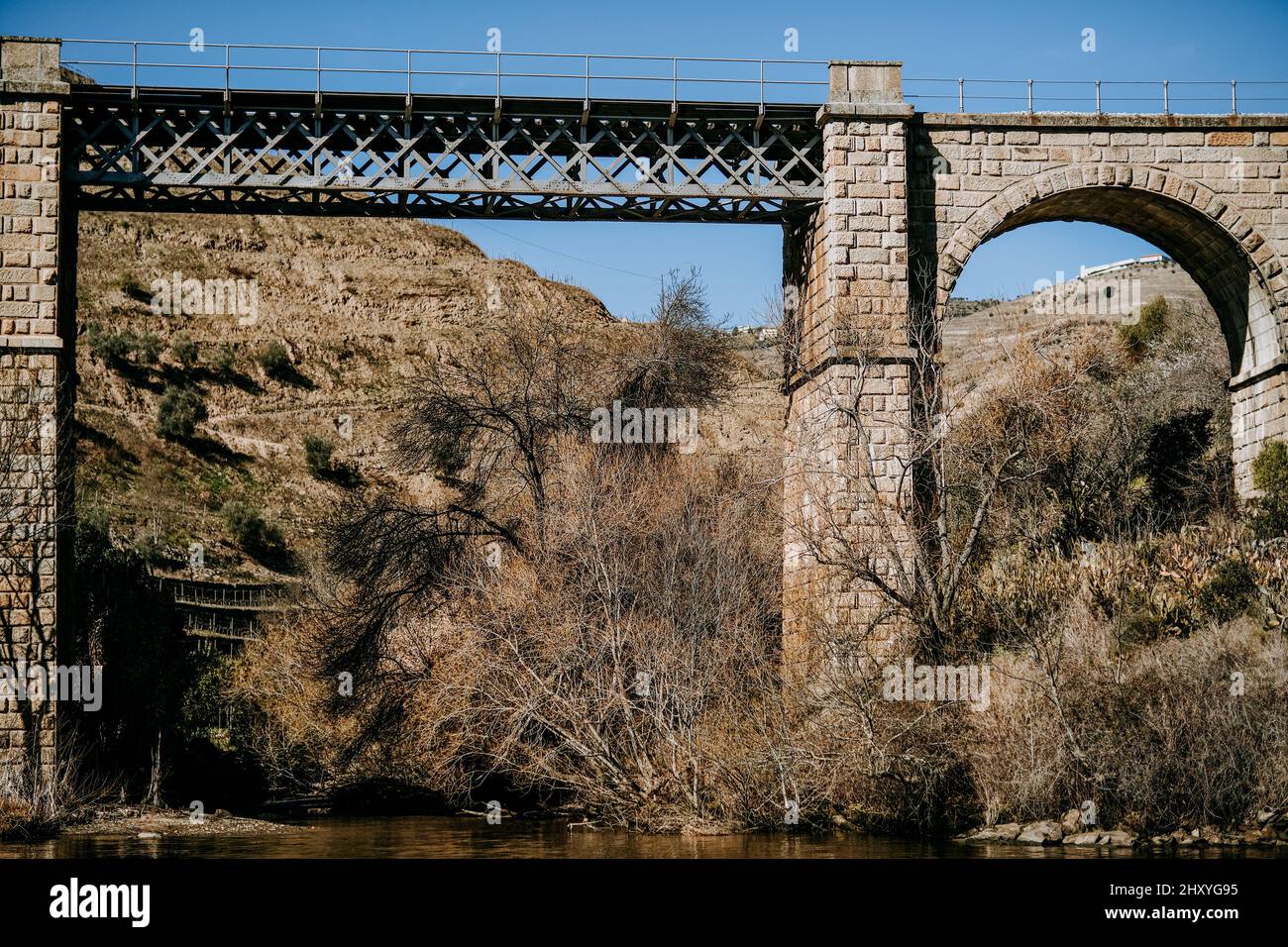 Old historic arch bridge surrounded by bushes by the Douro River ...