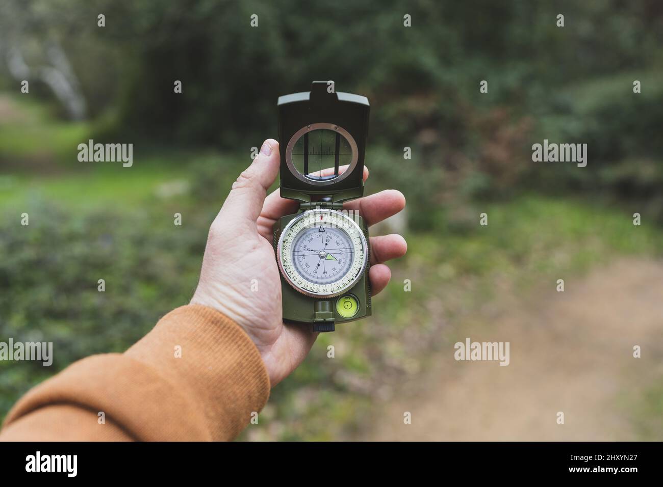 Closeup of a person's hand holding a compass on a blurry background ...