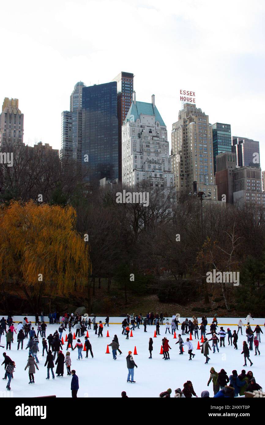 Vertical shot of people ice skating with NYC buildings in the ...