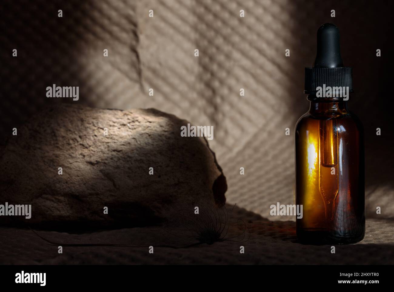 Brown glass bottle with a pipette on light brown background under a ...
