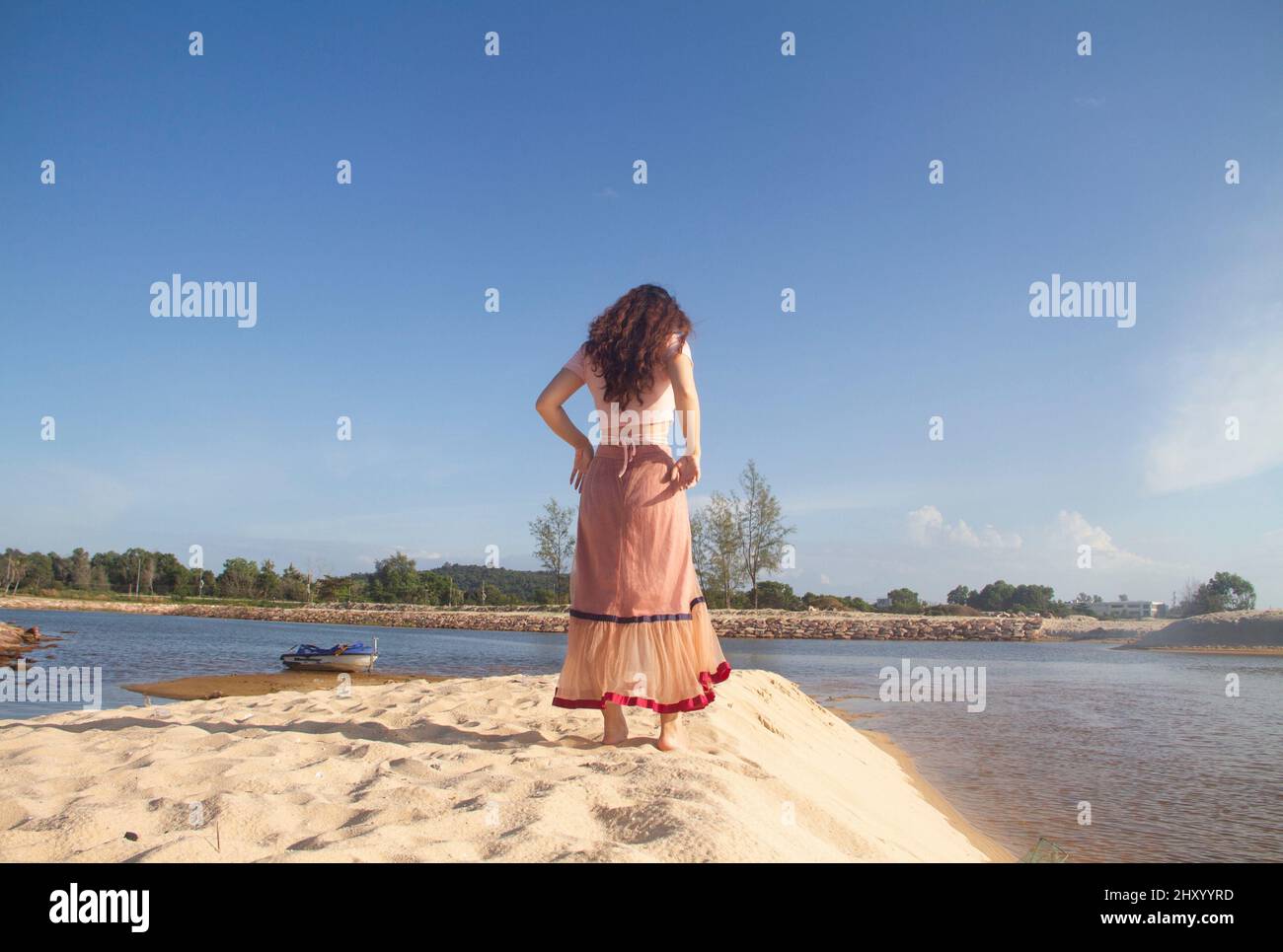 Vietnamese Female Wearing A Light Pink Dress Standing On A Sandy Beach