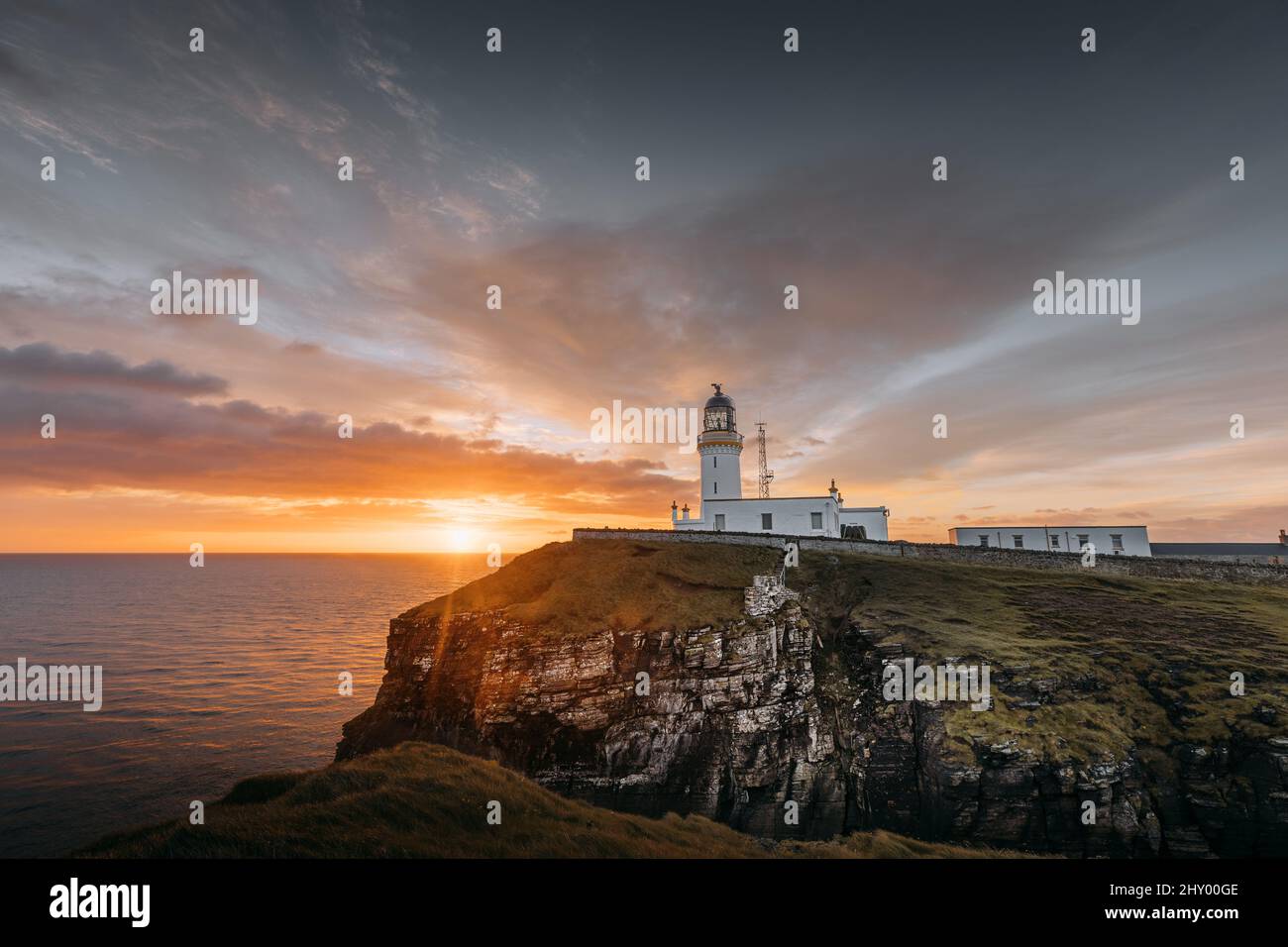 View of a lighthouse in Scotland during sunrise with dramatic clouds in ...