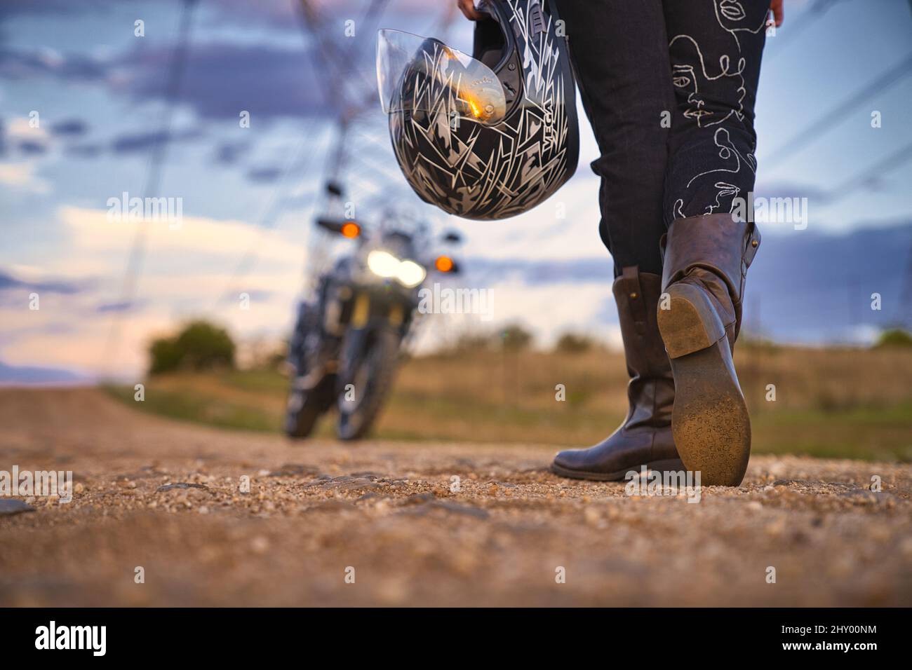 Low angle view of a female motorcyclist with boots holding a helmet in ...