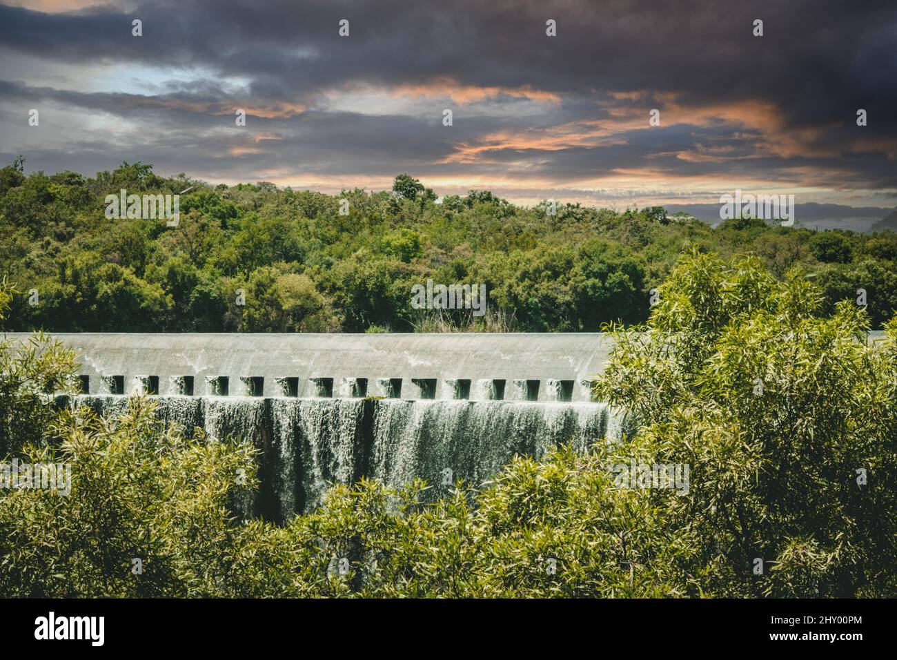 Beautiful landscape of a dam in a dense green forest under the cloudy ...