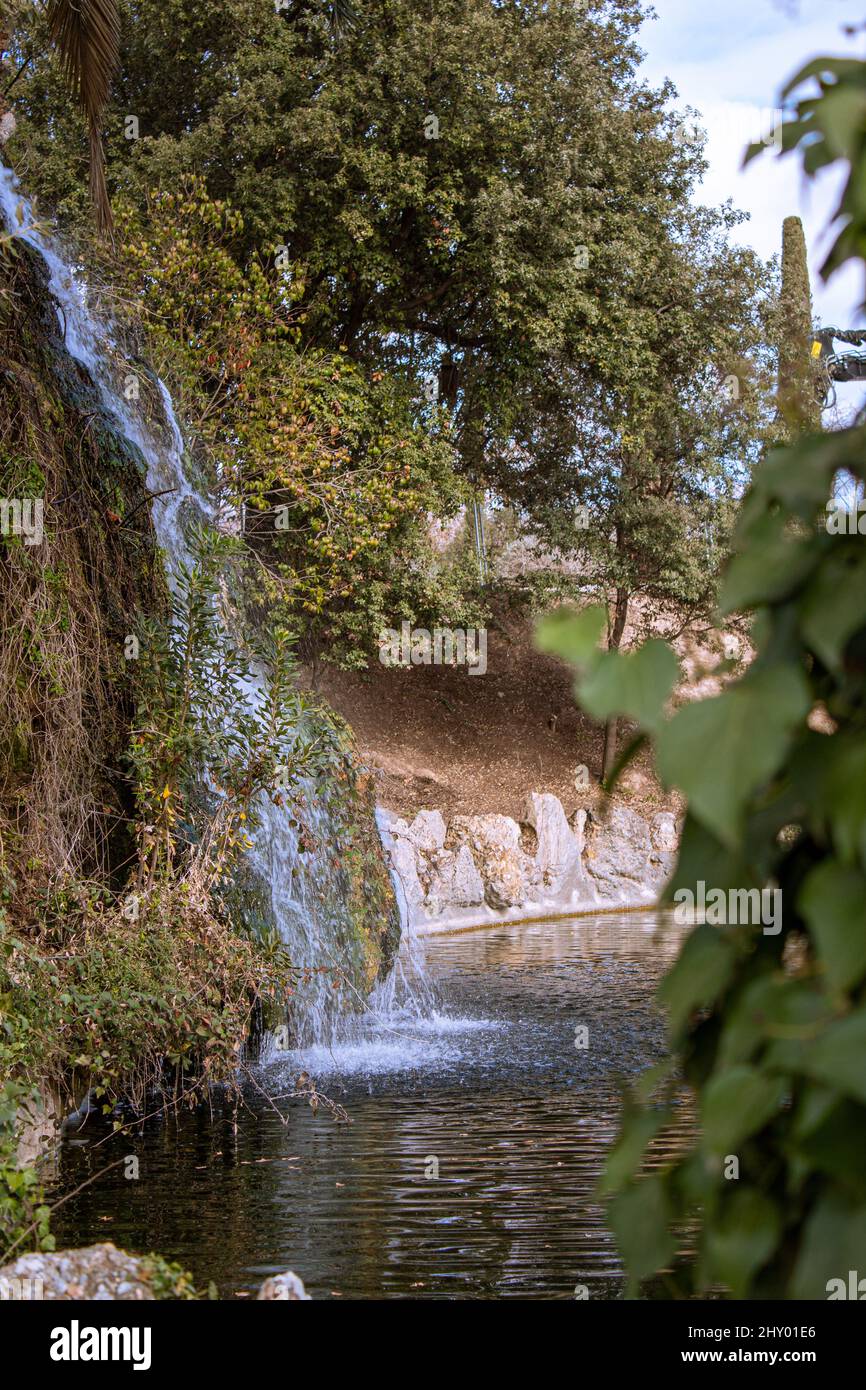 Vertical shot of a small waterfall flowing down the hill in a body of ...
