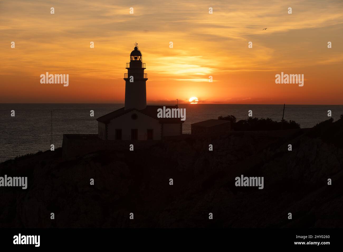 Mallorca Lighthouse during the sunrise against a dramatic orange sky ...