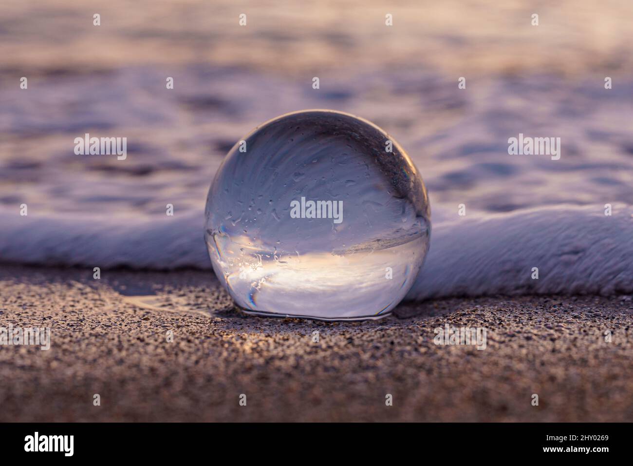 Glass ball reflecting the scenic sea at sunset Stock Photo - Alamy