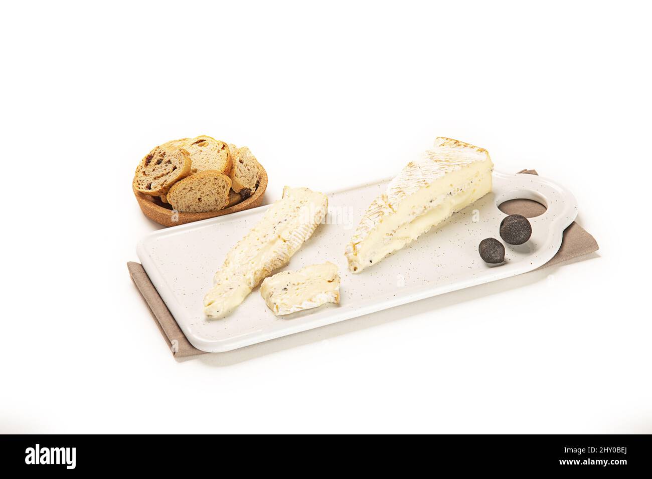 White plate with a piece of cheese, bread and truffles on the side ...