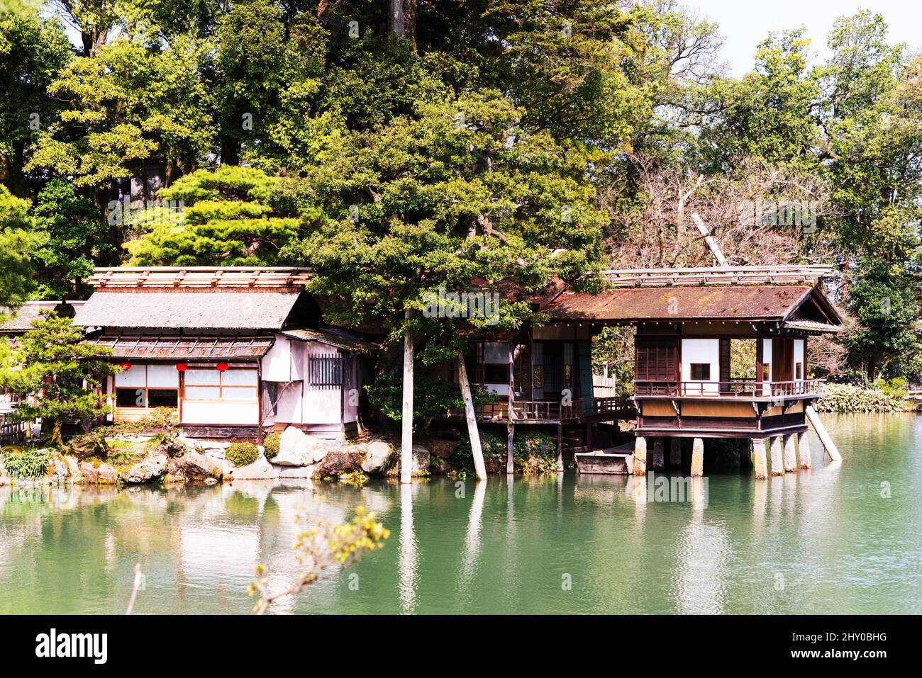 Rural houses on the water surrounded by dense trees in Kanazawa, Japan ...