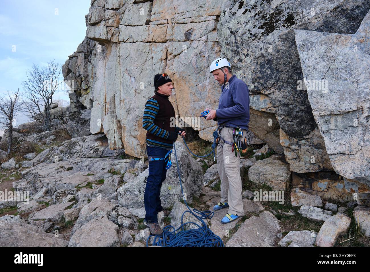 Male mountain guide instructs a climber at the start of a climbing ...