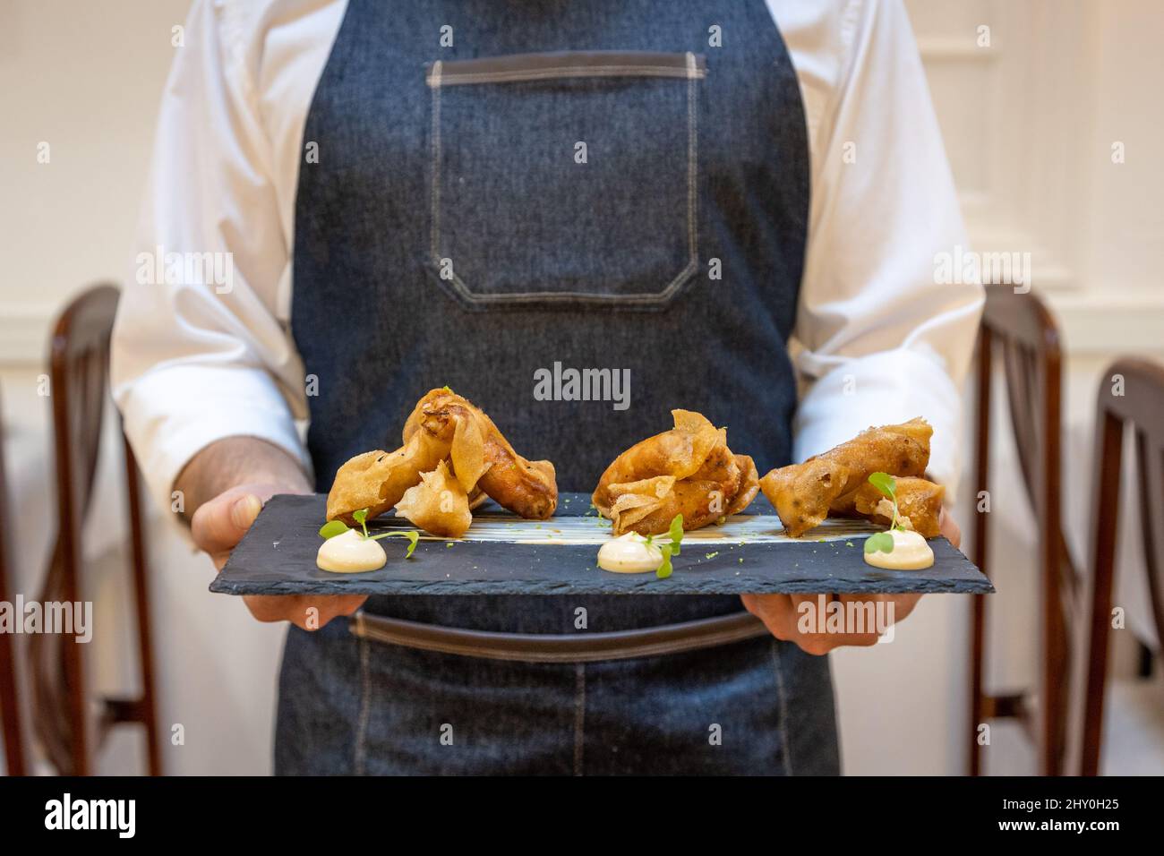 Waiter holding a fancy meal on a black plate in the restaurant Stock ...