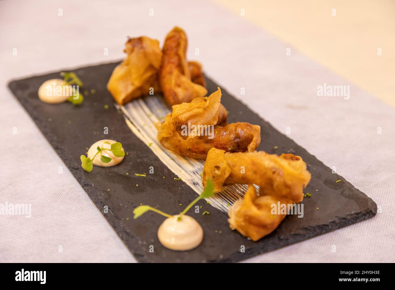 Fancy dish on a black plate with sauces on the side Stock Photo - Alamy