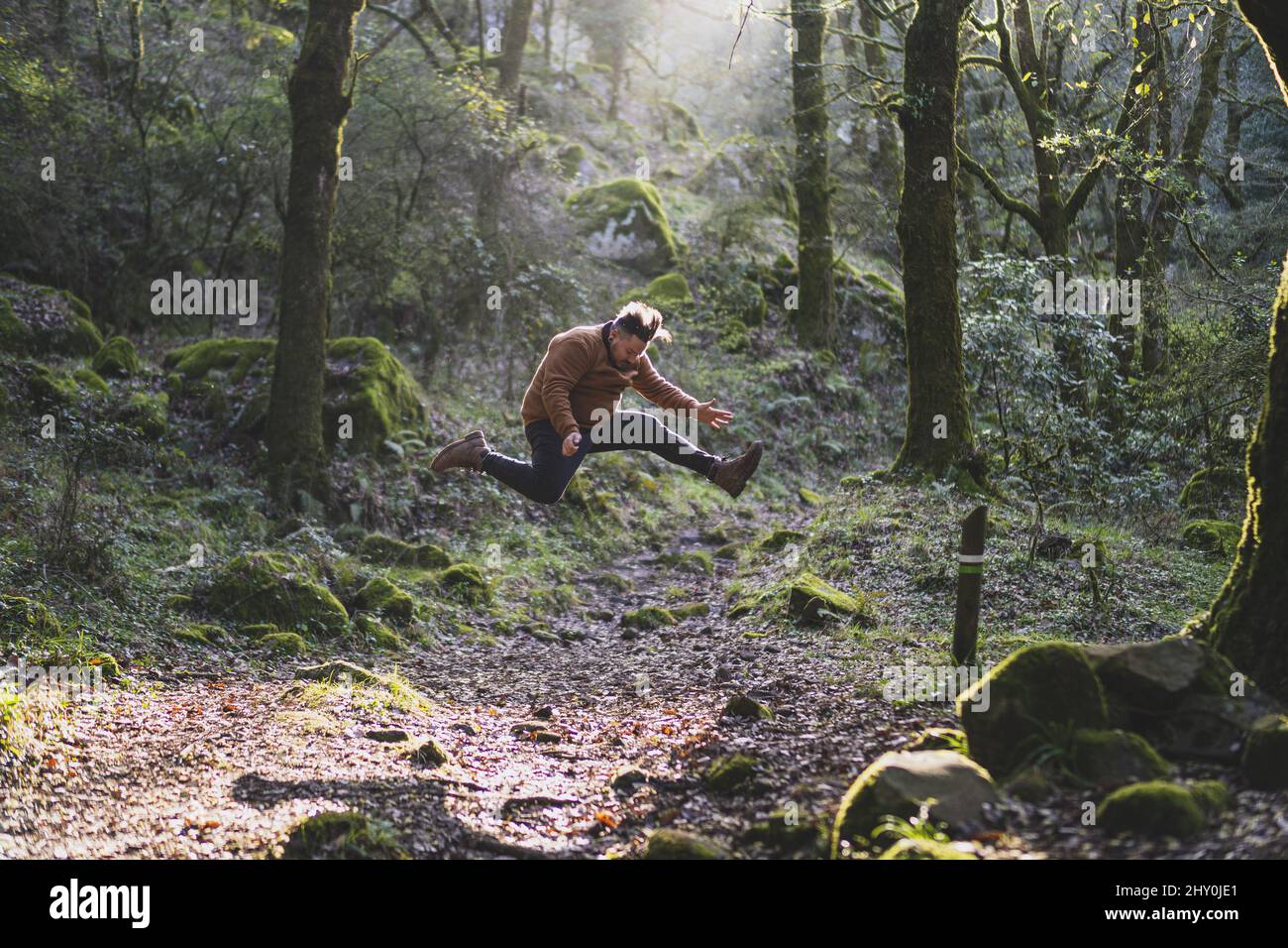 Funny male juping high during the hike in the lush green forest Stock ...