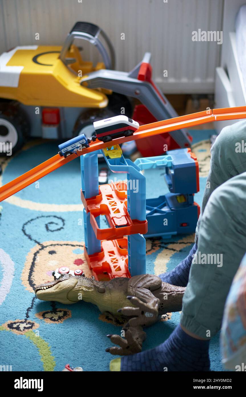Kid playing with a Hot Wheels track and combining it with toy trains in ...