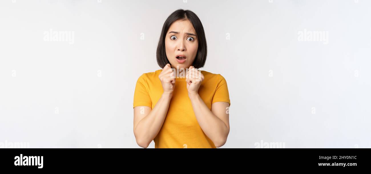 Portrait of scared asian woman shaking from fear, looking terrified and ...