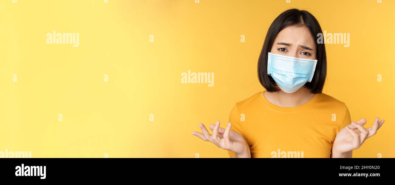 Close up portrait of confused asian woman in medical face mask ...