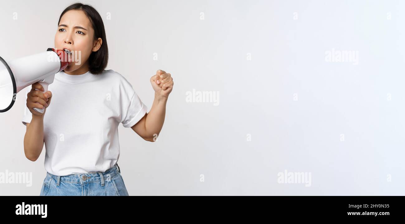 Asian girl shouting at megaphone, young activist protesting, using loud ...