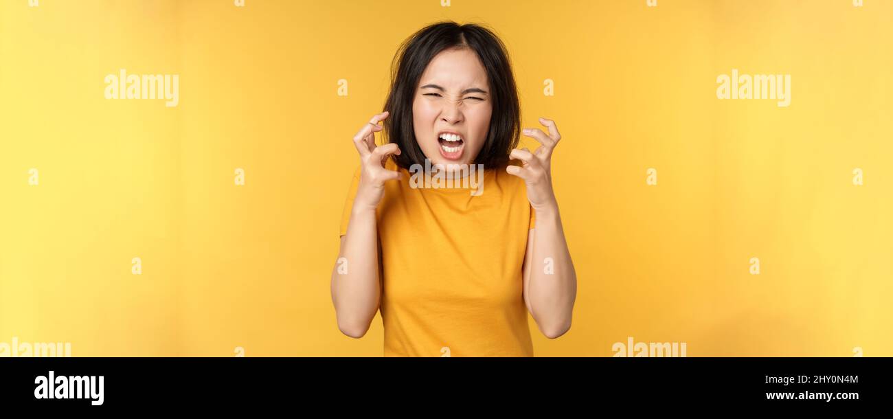 Image of angry asian woman, shouting and cursing, looking outraged ...