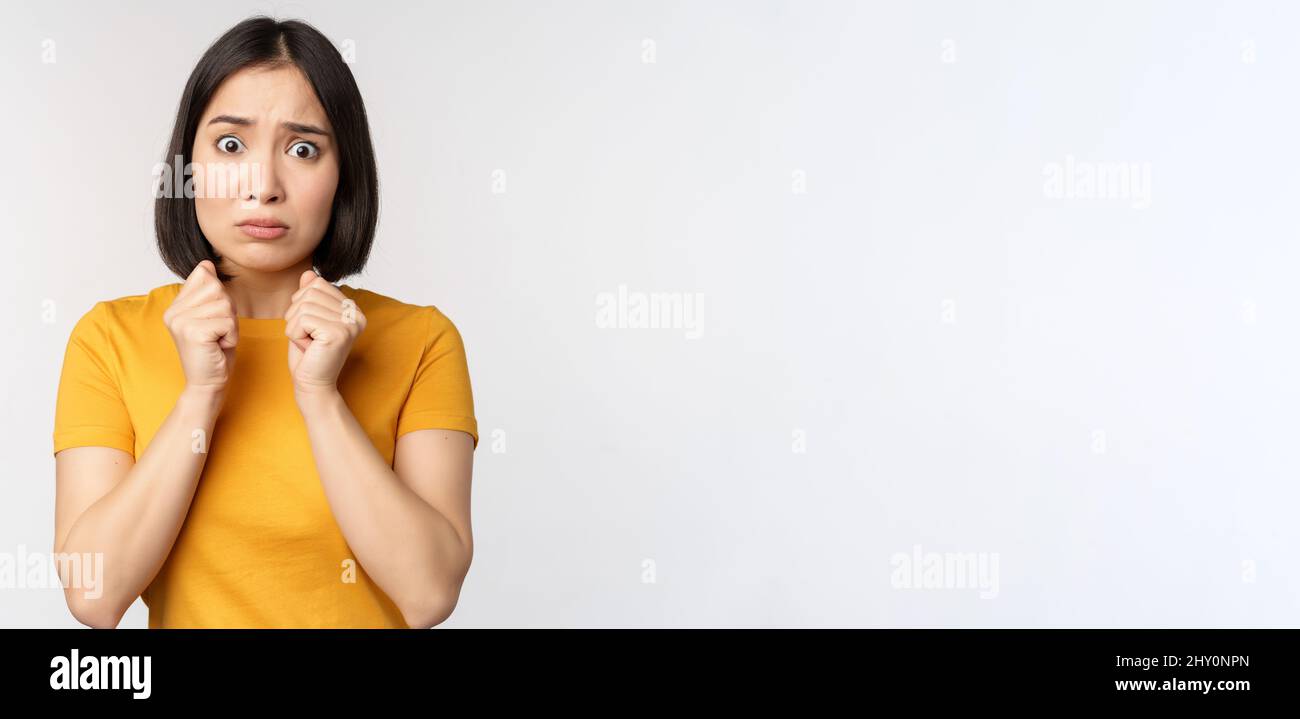 Portrait of scared asian woman shaking from fear, looking terrified and ...