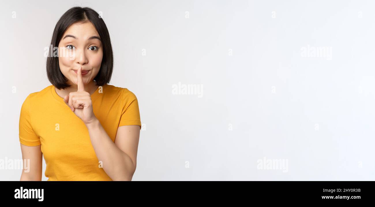 Keep quiet. Cute asian woman make shhh gest, showing shush, hush sign ...