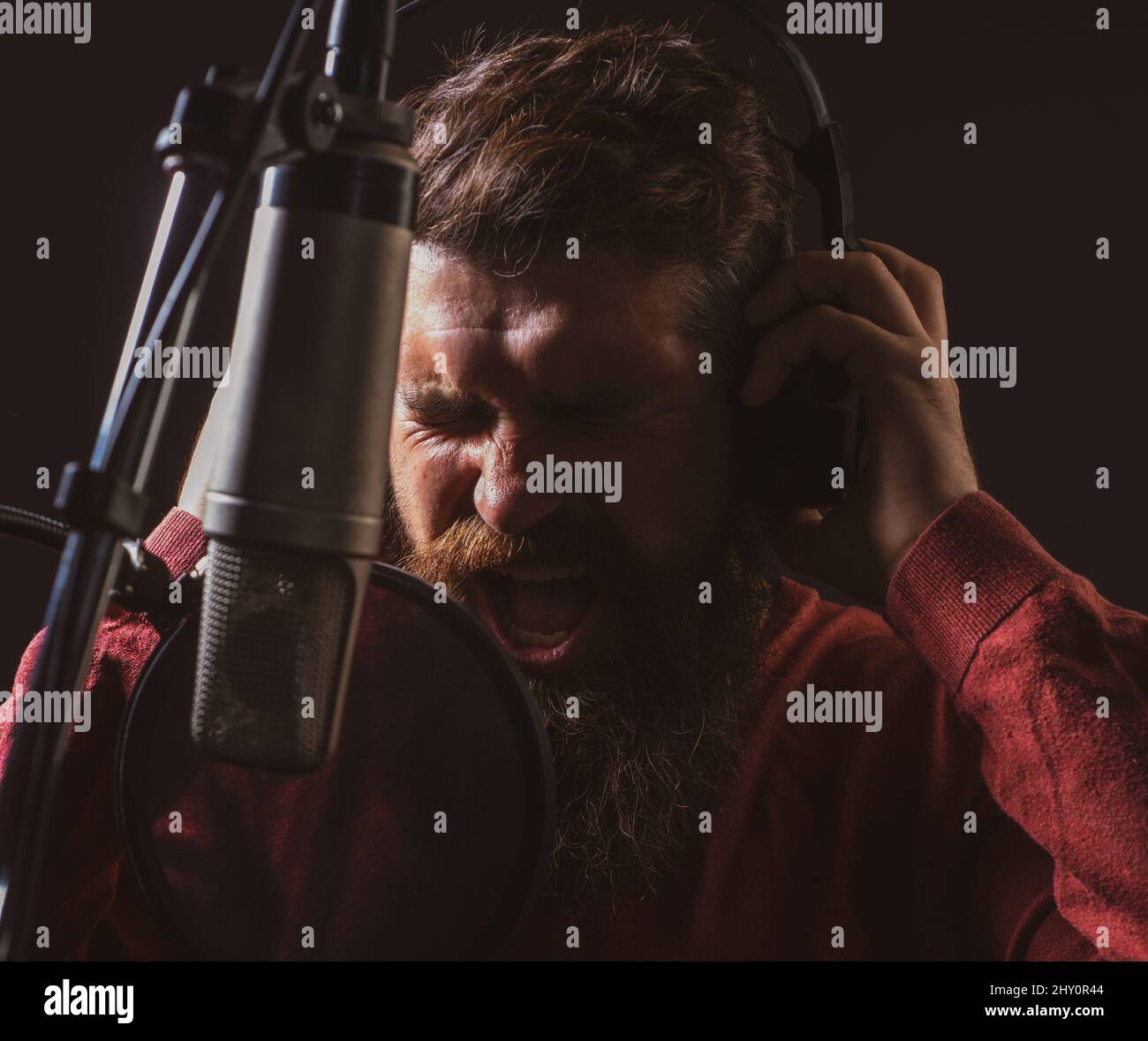 Singer wearing headphones is performing a song with a microphone while ...