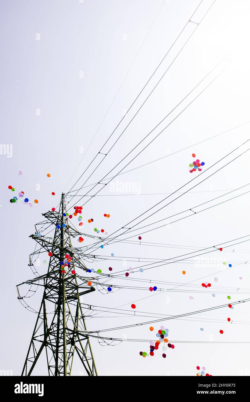 Vertical shot of a transmission tower with colorful balloons flying ...