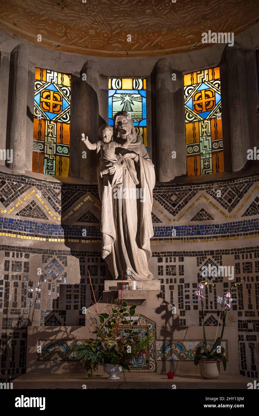 White stone statue of the Virgin Mary in a church in France in front of ...