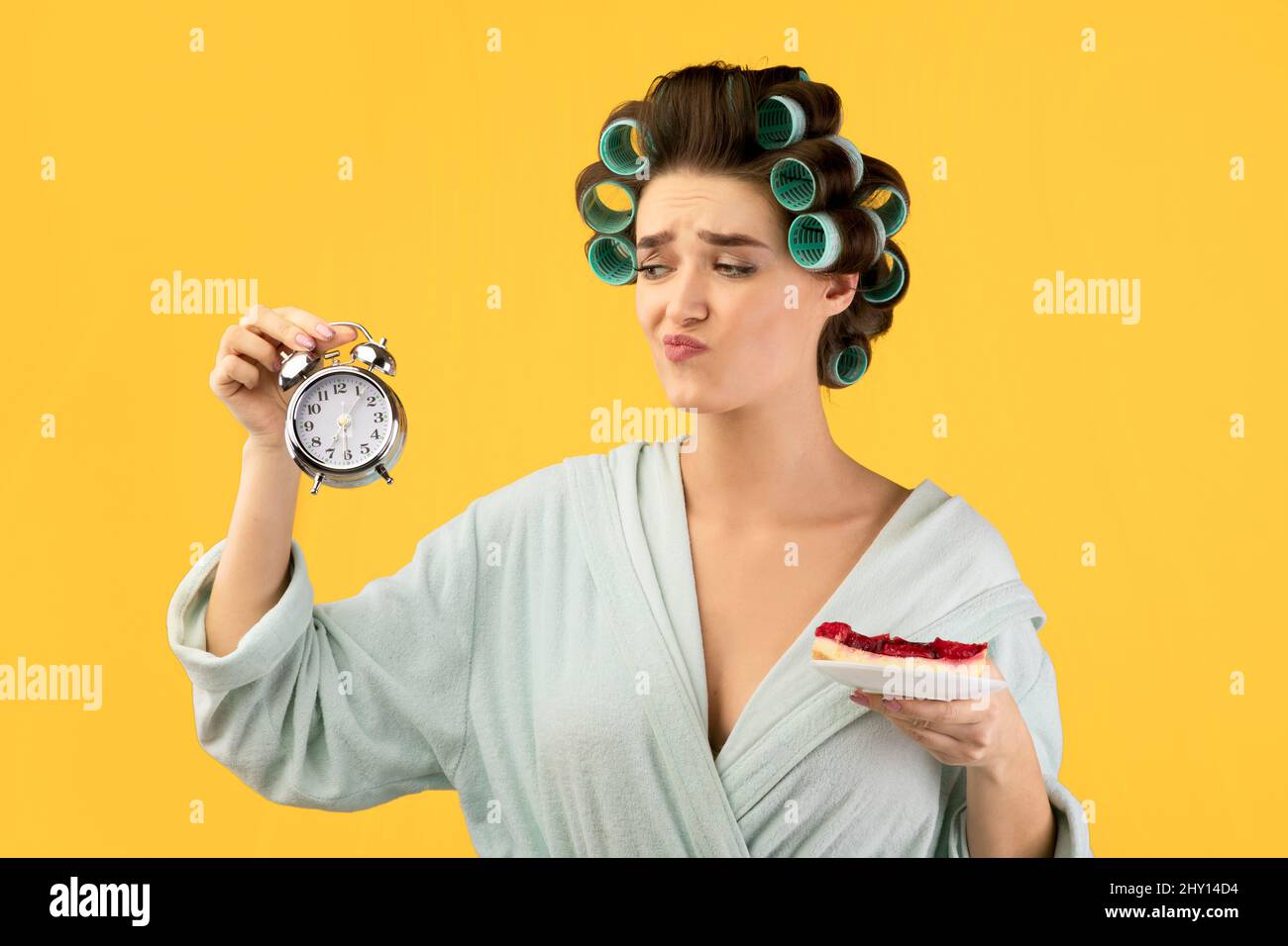 Hungry Glamorous Female Holding Cake And Clock Over Yellow Background ...