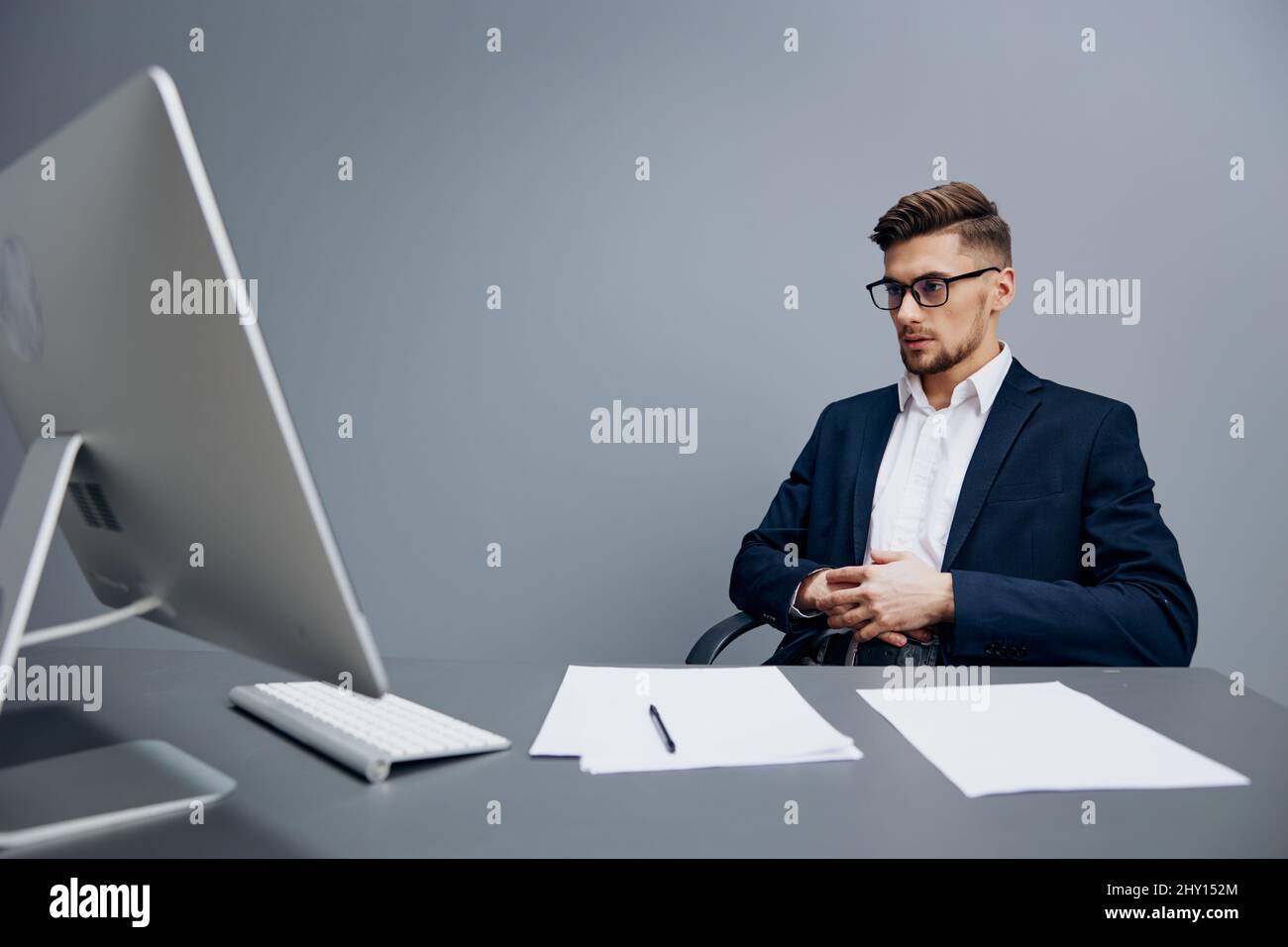 manager wearing glasses works in front of a computer Gray background ...