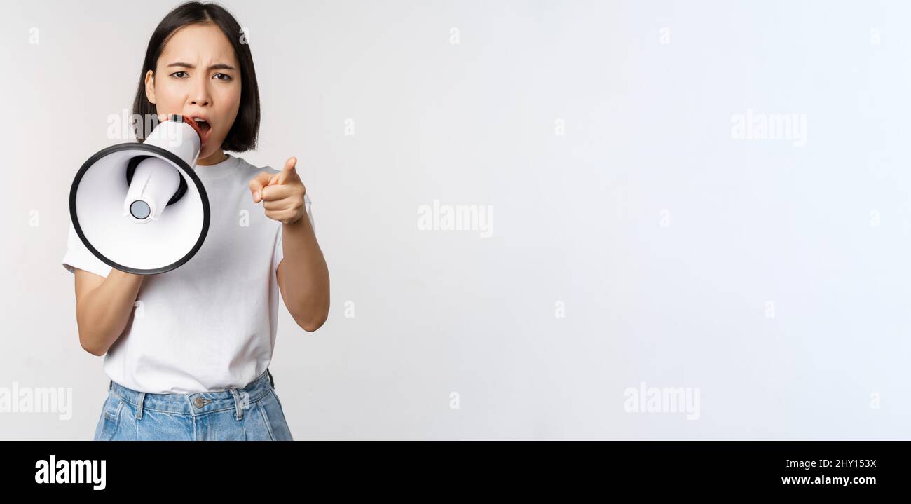 Angry asian woman with megaphone, scolding, accusing someone ...