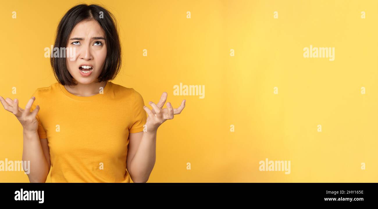 Image of angry asian woman, shouting and cursing, looking outraged ...